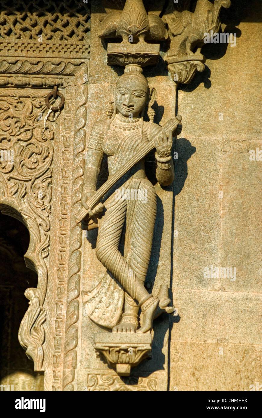 Woman playing veena musical instrument carved in stone on the wall of ...