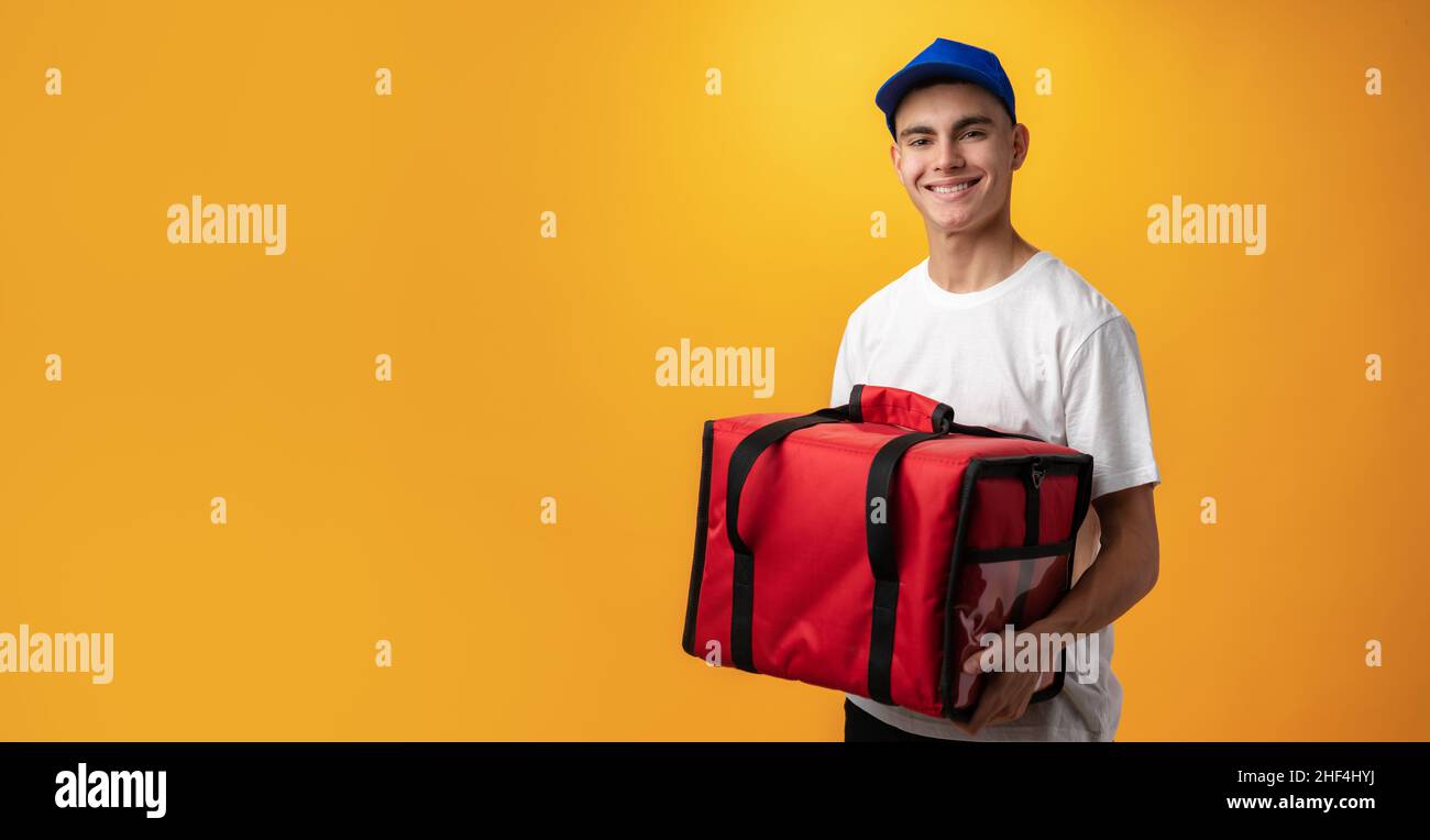 Portrait of pizza delivery boy with thermal bag against yellow ...