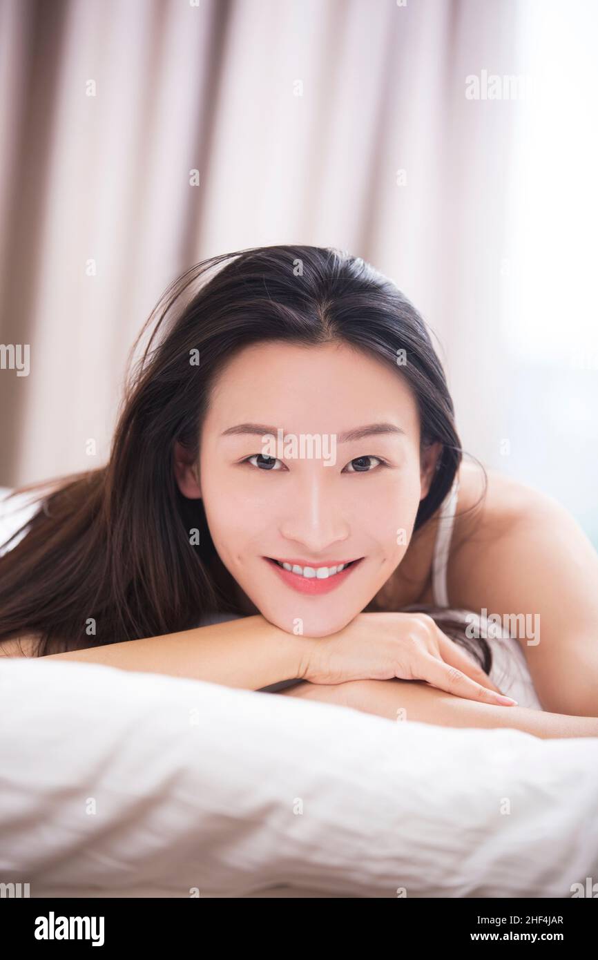 Young woman lying in bed Stock Photo - Alamy