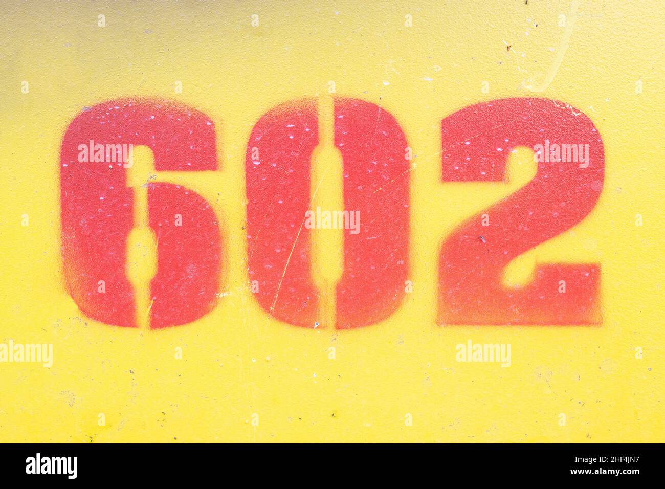 A number 602 in red on yellow, painted in an irregular pattern on an ...