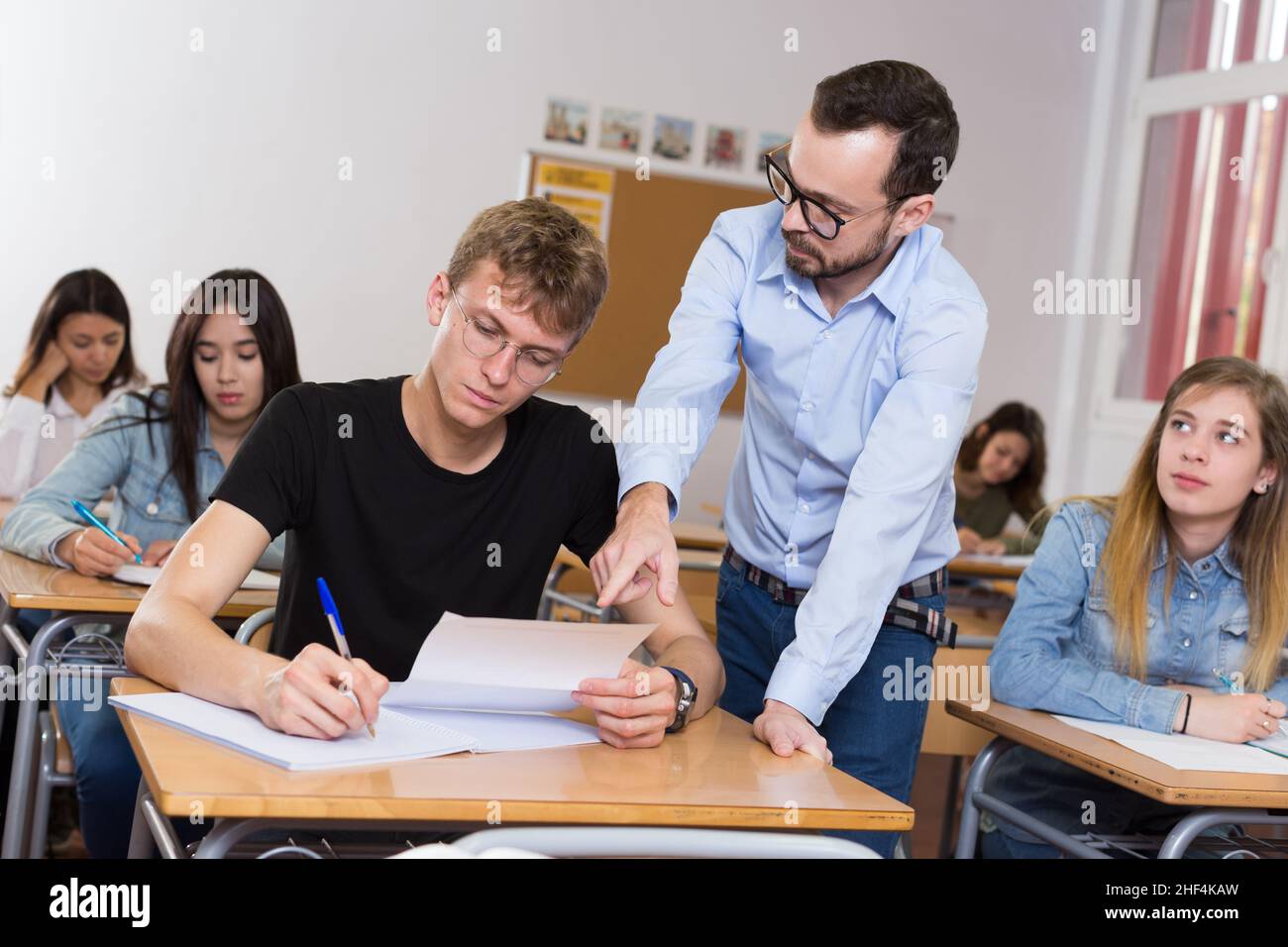 Young boy is writing test and teacher is explaining about questions ...