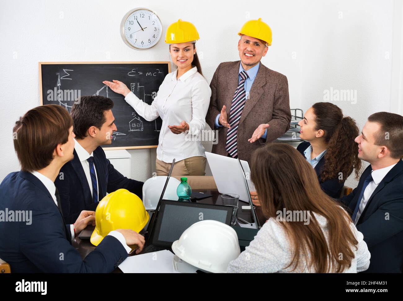 Positive professionals with laptops and helmets Stock Photo - Alamy