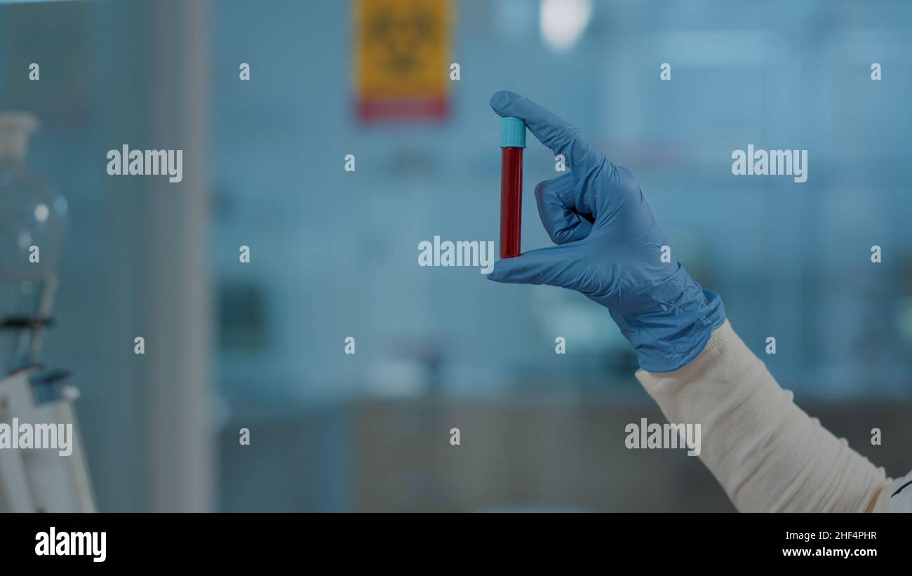 Lab worker holding red substance in test tube for science analysis ...