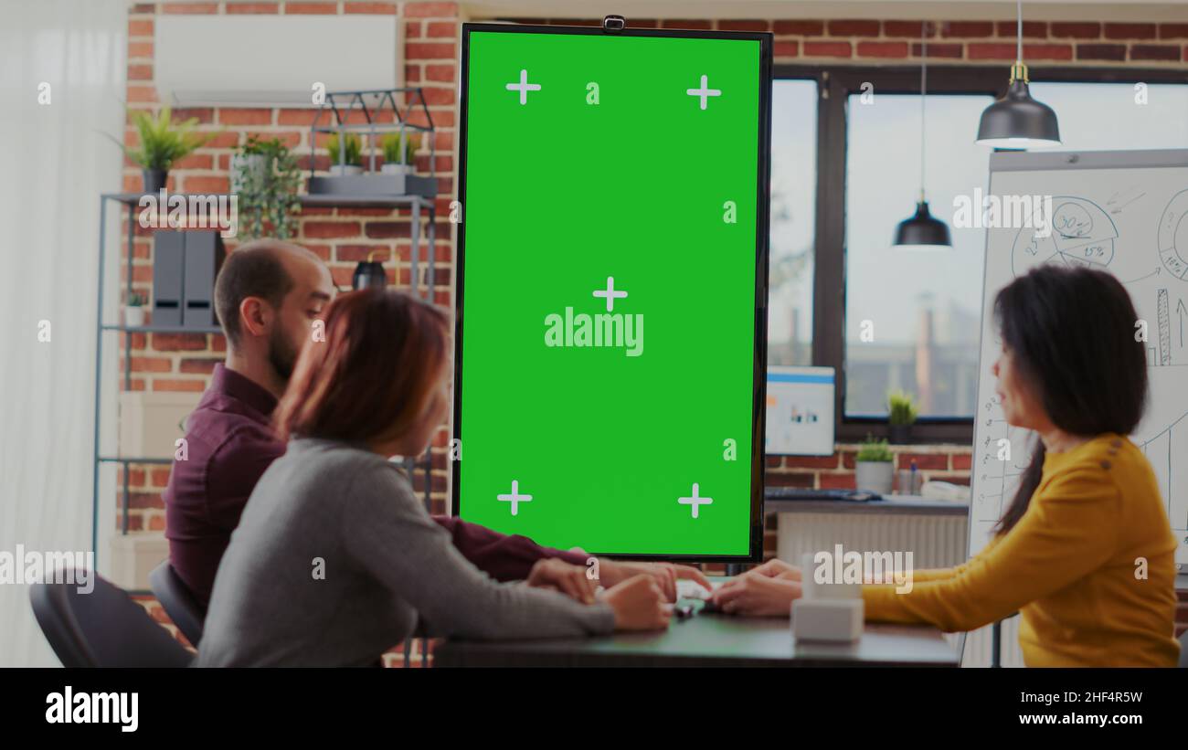 Coworkers meeting in office with green screen on monitor vertically to ...