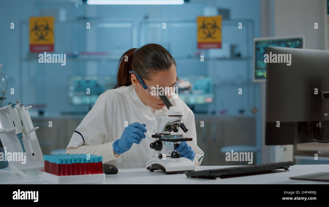 Portrait of chemist working with microscope in laboratory, to develop ...