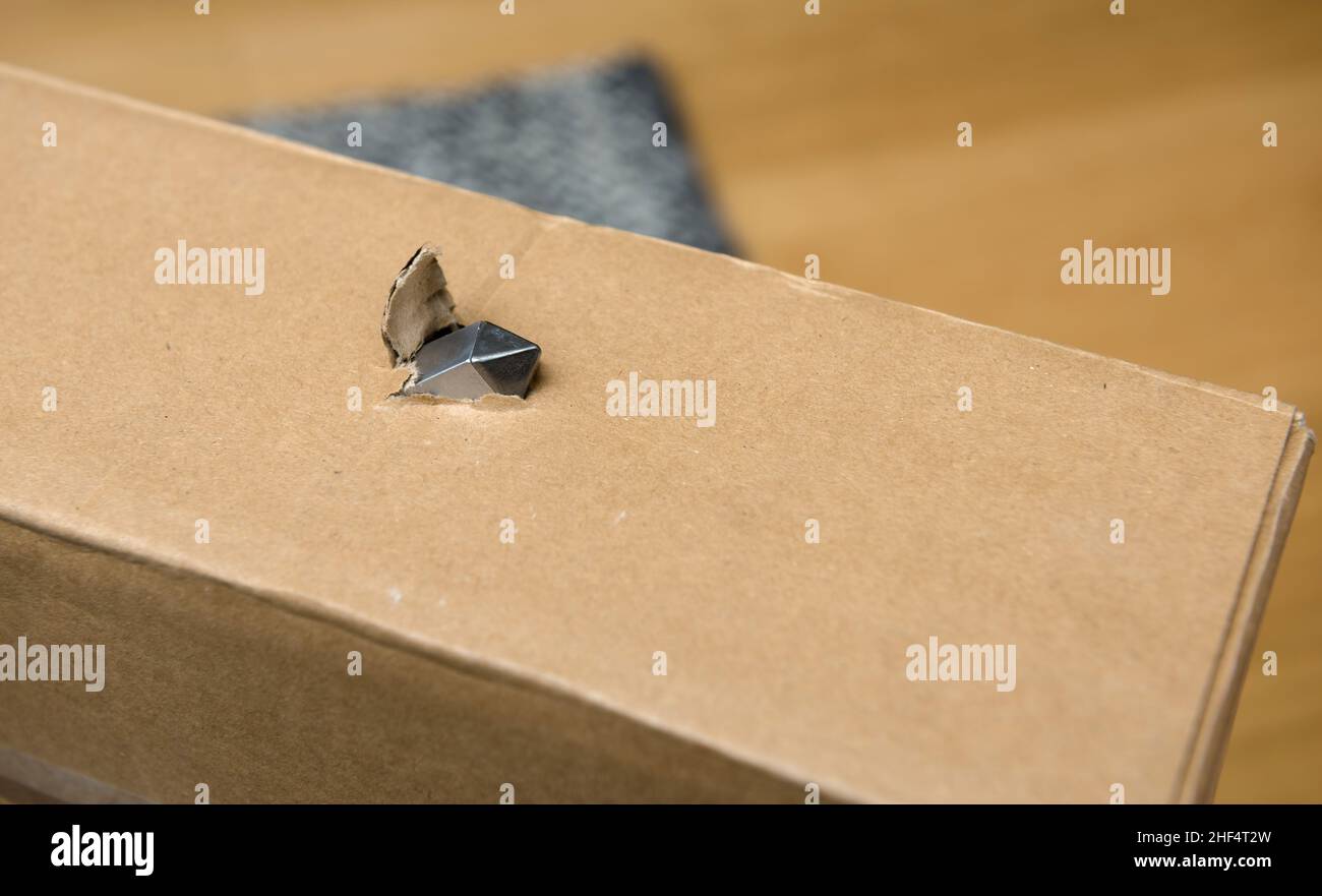 Damaged parcel cardboard with a steel sharp object inside - concept for ...