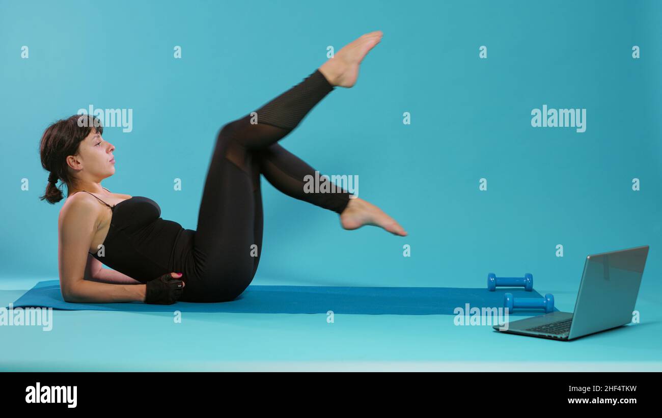 Fit woman training legs muscles with bicycle exercise over blue ...