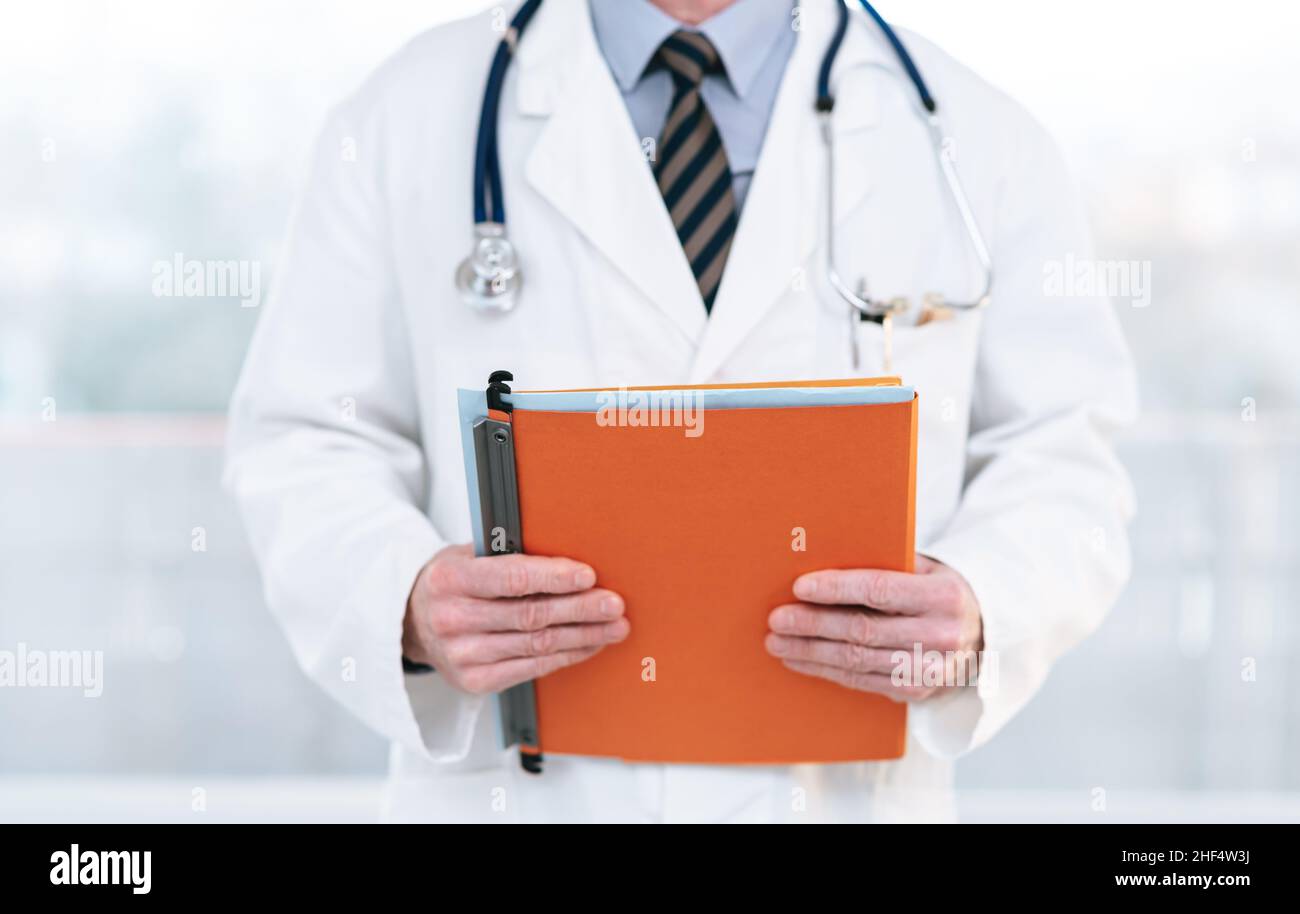 Doctor standing and holding a folder Stock Photo - Alamy