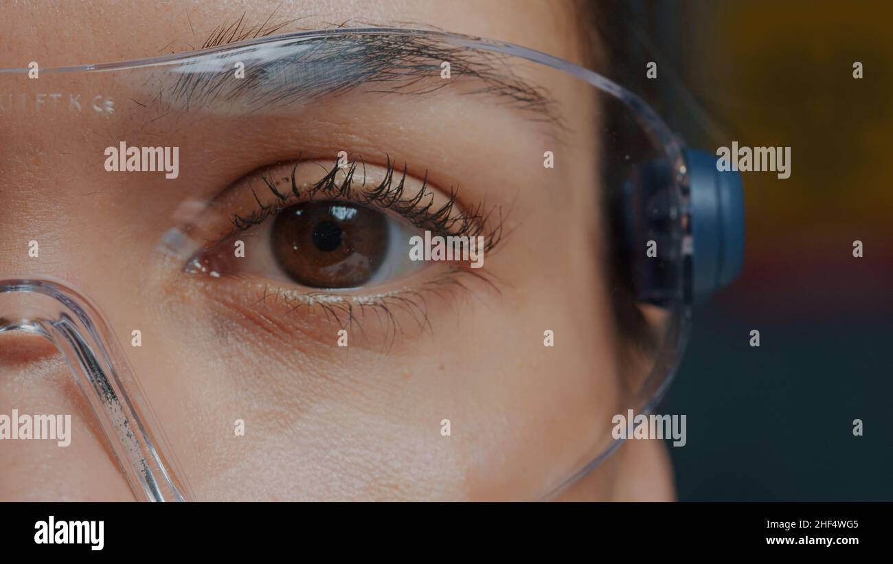Woman with protective glasses showing one eye in front of camera, brown ...