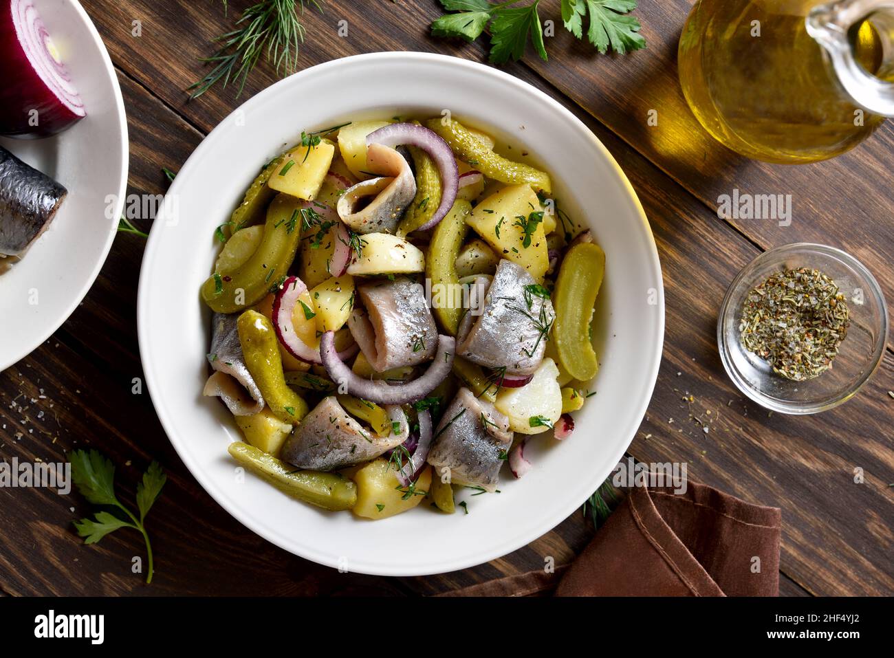 Herring salad with boiled potatoes, pickled cucumbers and red onion in ...
