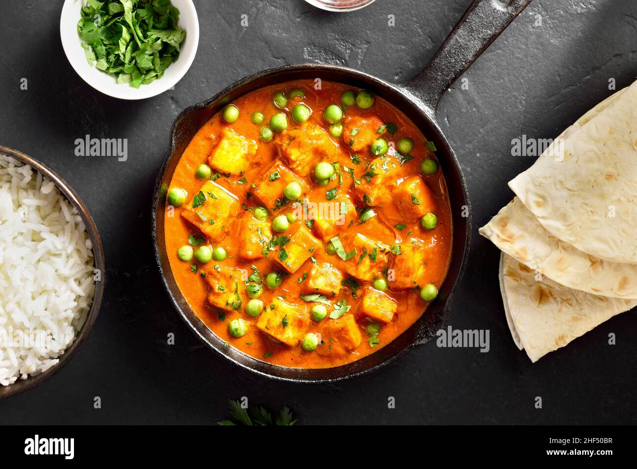 Indian style cottage cheese curry in pan on black stone background. Top ...