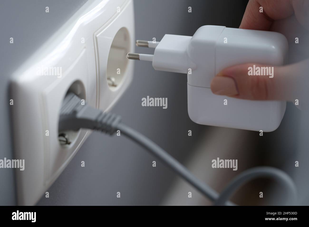 Female fingers plug the power adapter into an outlet Stock Photo - Alamy