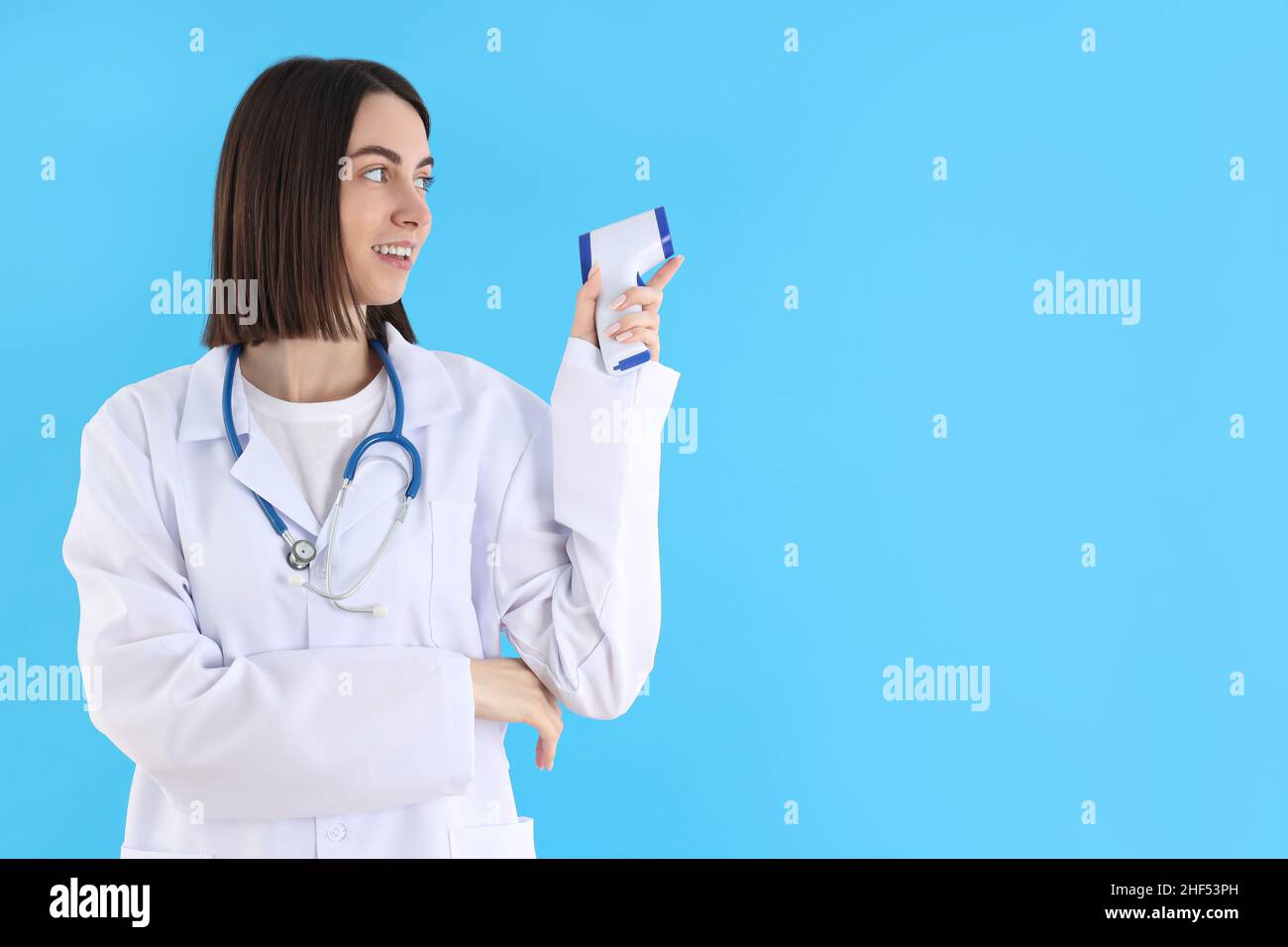Female trainee doctor with thermometer gun on blue background Stock ...