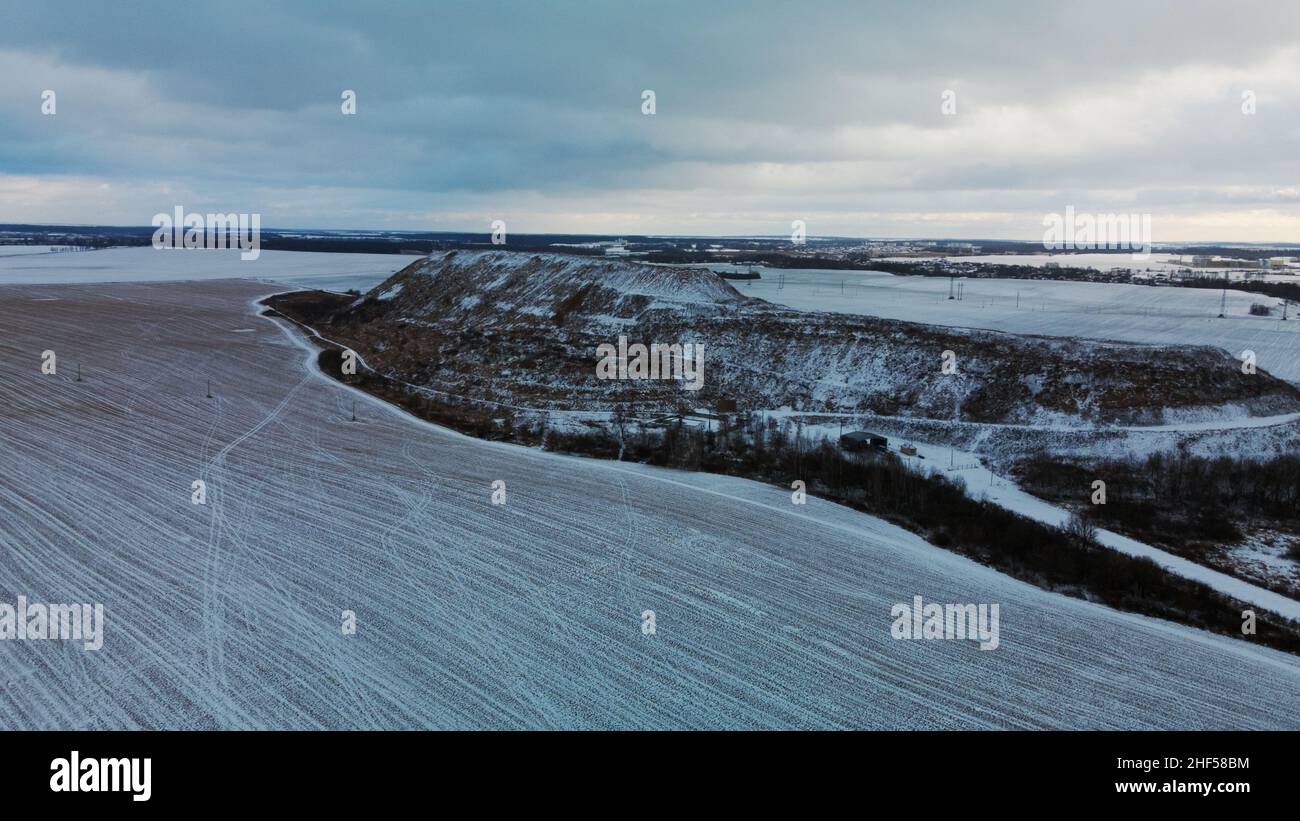 Flying over a snowy field. The city dump is visible, covered with snow ...