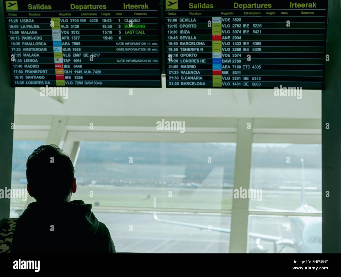 A man looking at information departure board and checking his flight in ...