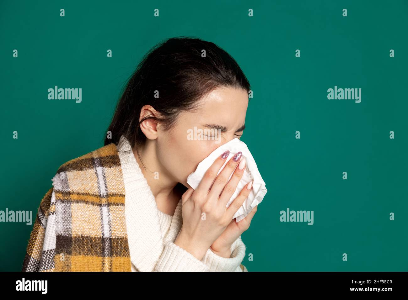 Portrait of young beautiful girl has a cold isolated on green studio ...