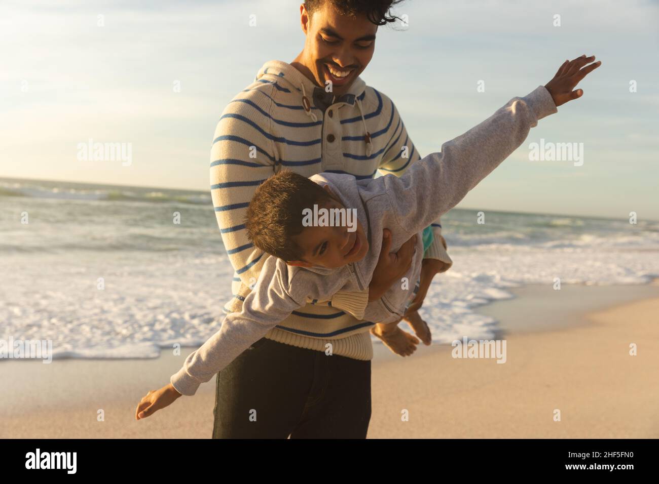 Happy biracial man carrying son pretending to fly with arms ...