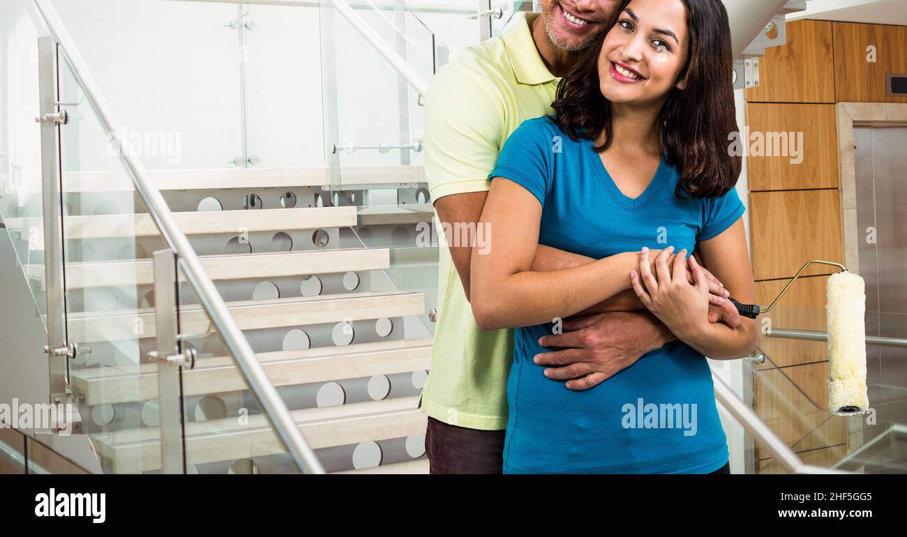 Composite image of caucasian couple hugging and smiling against stairs ...