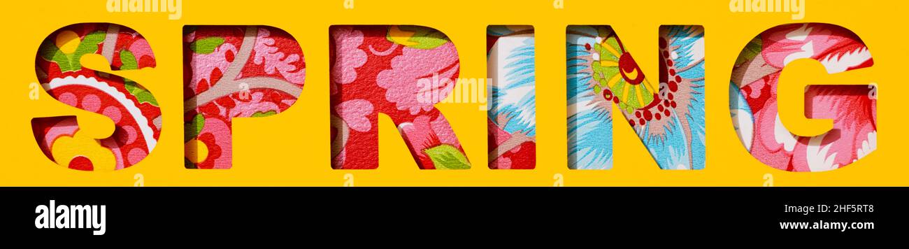 the word spring, cut out on a yellow paper, and a floral background ...