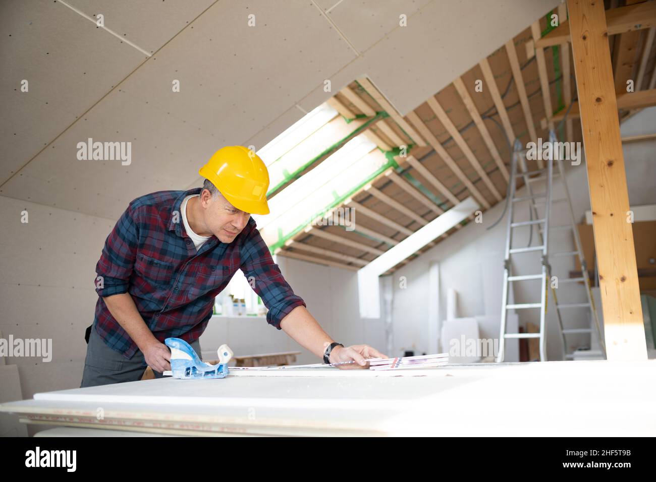 man on building site with yellow helmet works in drywall construction ...