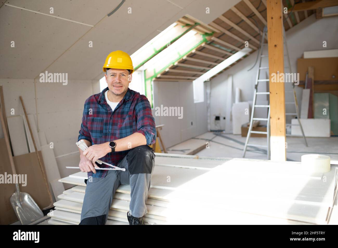 man on building site with yellow helmet works in drywall construction ...