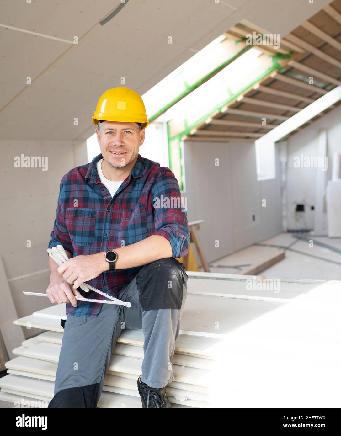 man on building site with yellow helmet works in drywall construction ...