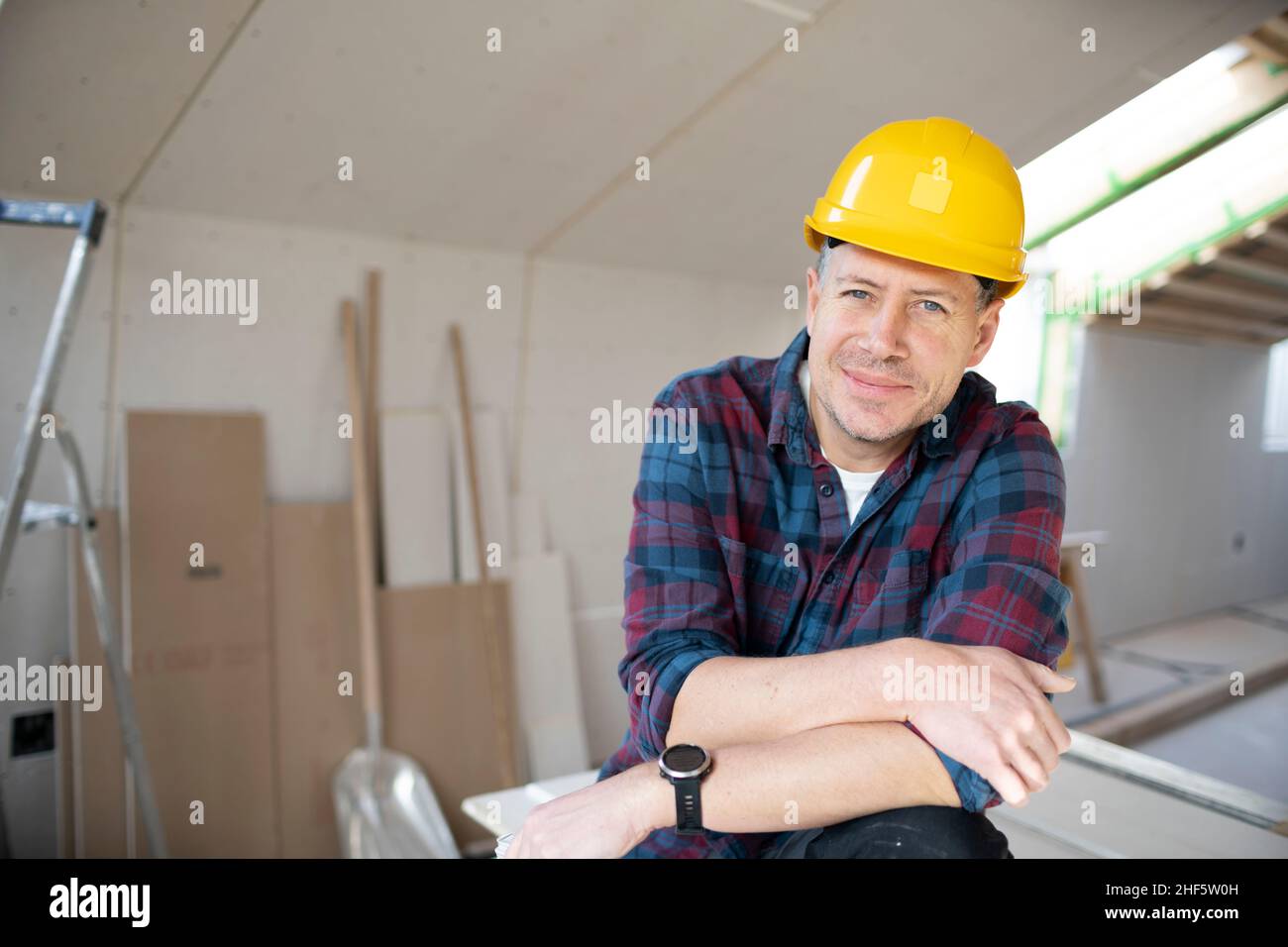 man on building site with yellow helmet works in drywall construction ...