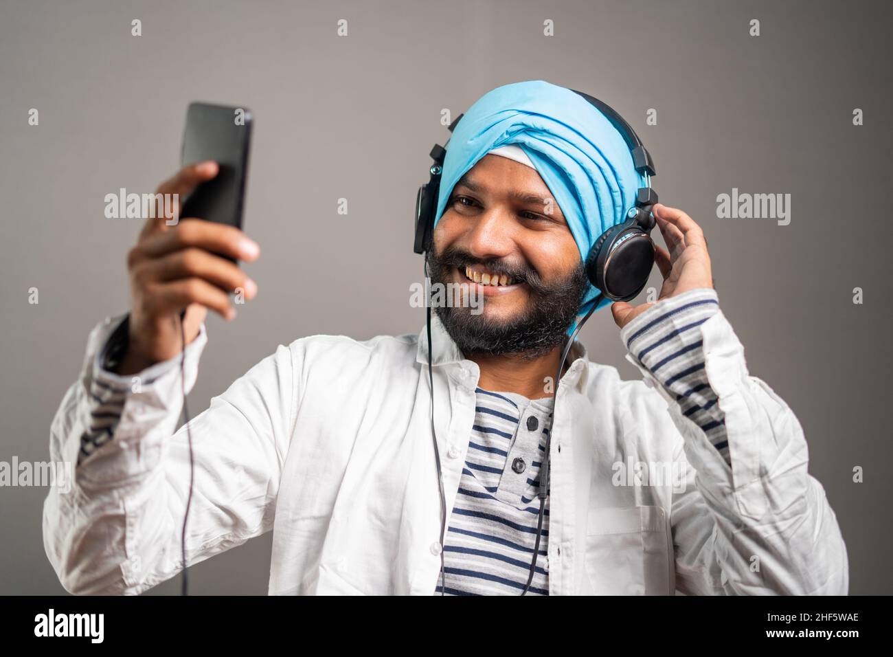 young indian sikh man relaxing by listeninng music on mobile phone by ...
