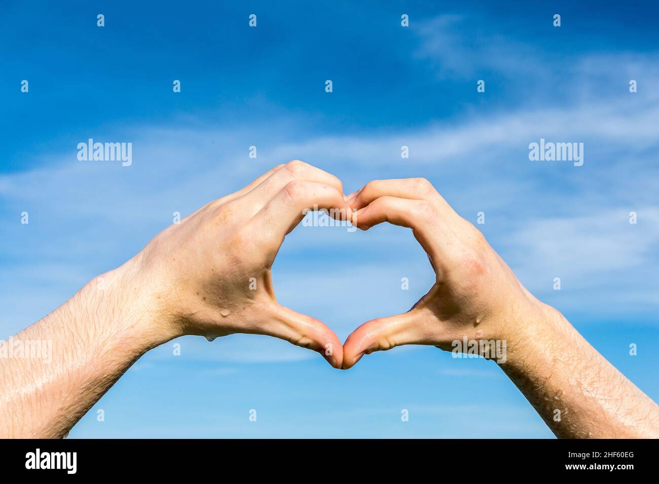 heart shape with hand under blue sky in sun Stock Photo - Alamy