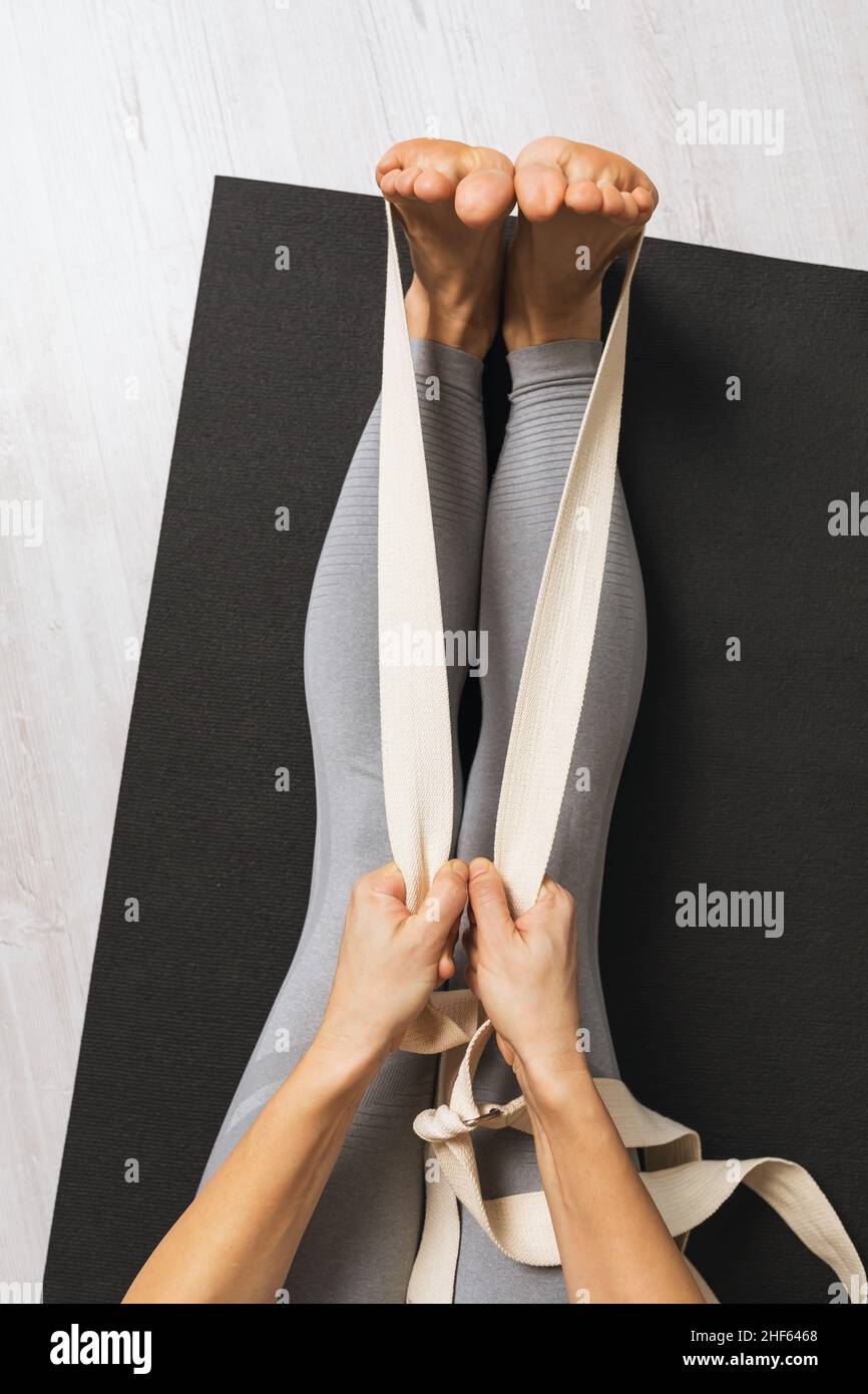 Woman performs an exercise with straps, to stretch the muscles of the ...