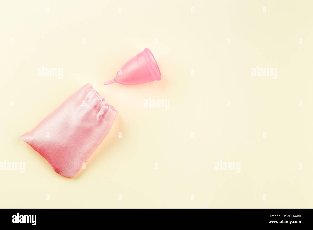 Pink Silicone Menstrual Cup near pink Storage Cloth Bag over beige ...