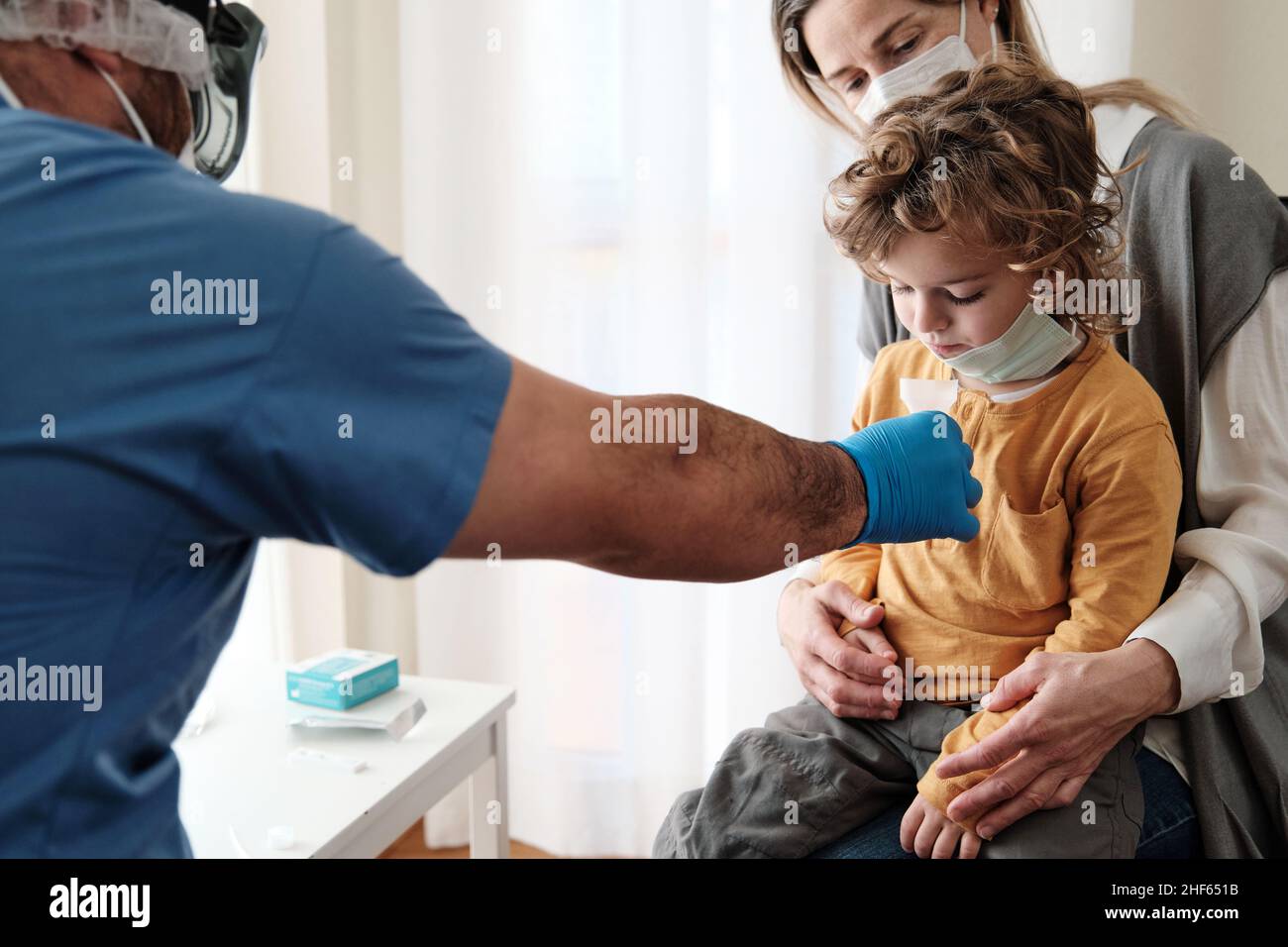 A nurse collecting saliva sample from child with mother Stock Photo - Alamy