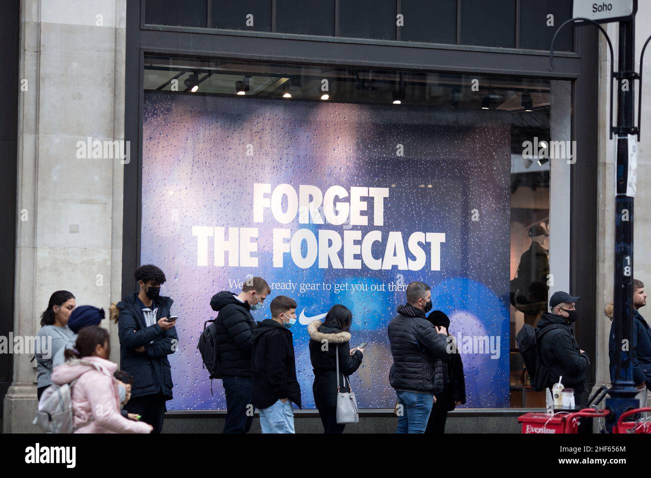 People queue in front of an advertisement reading ‘Forget the Forecast ...