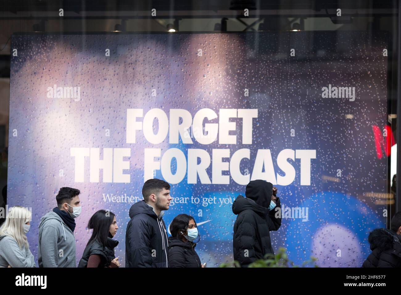 People queue in front of an advertisement reading ‘Forget the Forecast ...