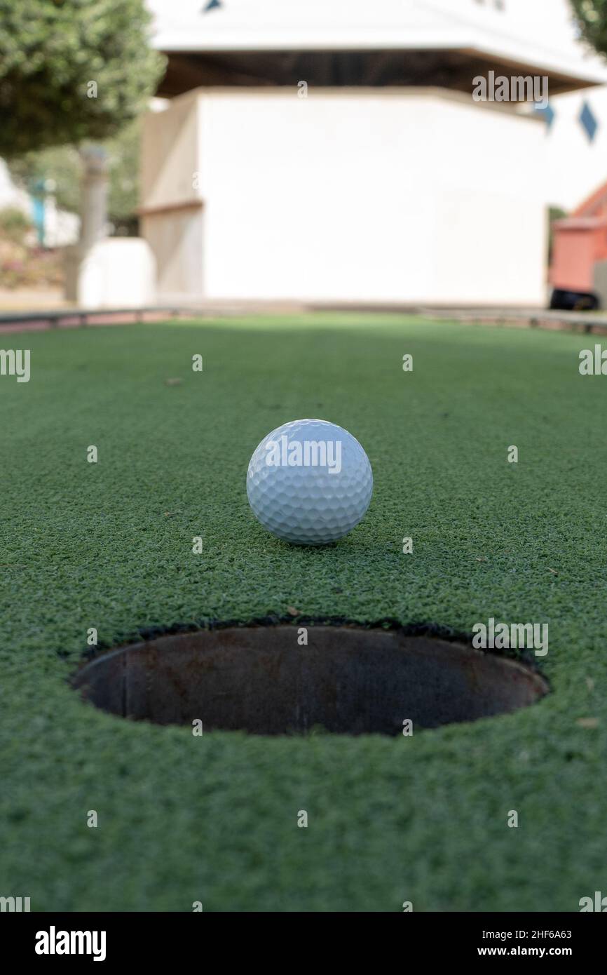 Miniature or mini golf hole close up with ball in center on green ...