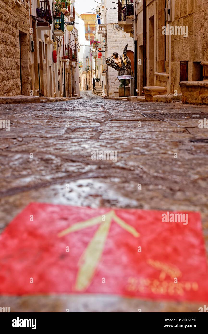 A golden arrow on a red background in an alley of Putignano, Italy ...