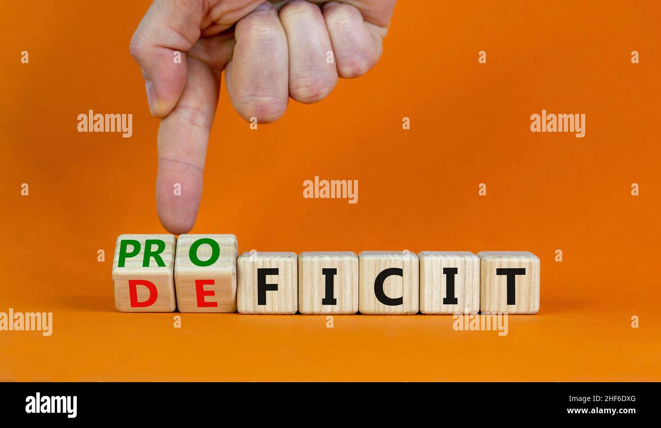 Proficit or deficit symbol. Businessman turns cubes, changes the word deficit to proficit ...