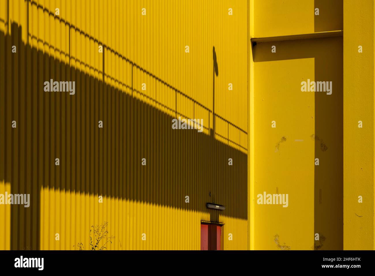 Yellow warehouse, shadow, red gate Stock Photo - Alamy