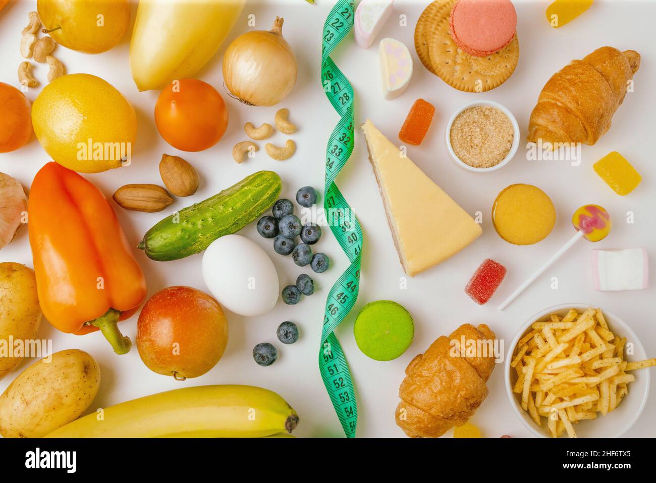 Various useful and unhealthy food items with measuring tape on white ...