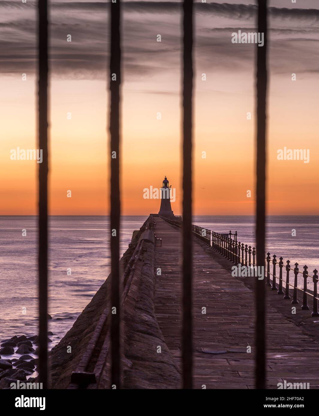 Tynemouth Pier and the Lighthouse through the metal railings with a ...