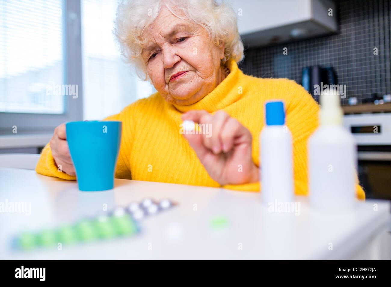 Ill old woman taking a pill from a pill dispenser in her house Stock ...