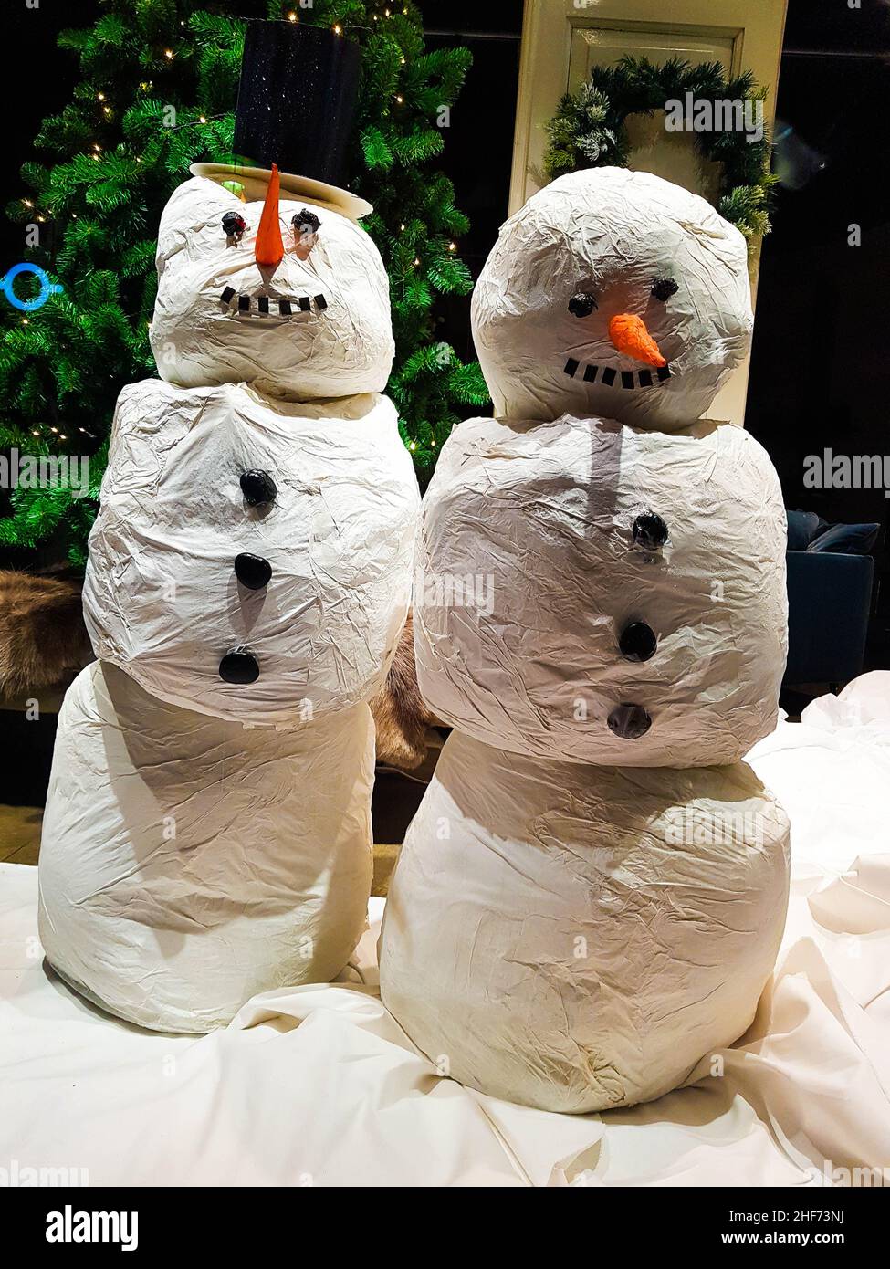 Two snowmen in white with a carrot nose and coal buttons in a store ...