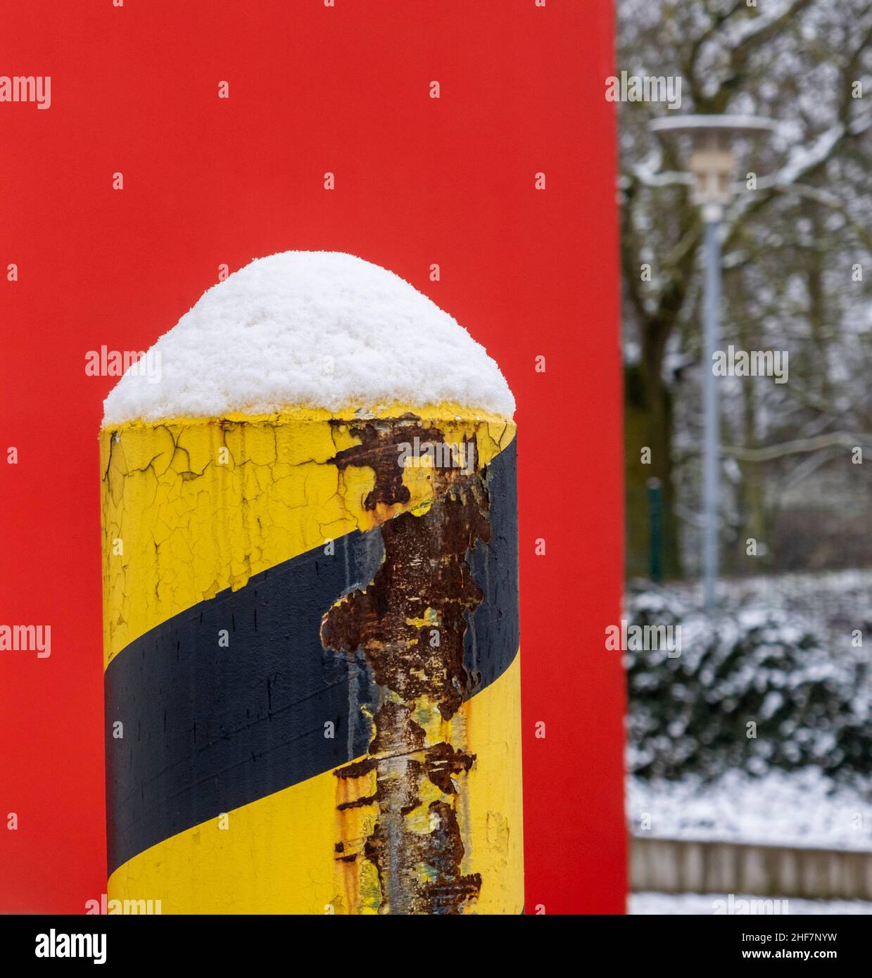First snow, yellow black bollard, red wall Stock Photo - Alamy