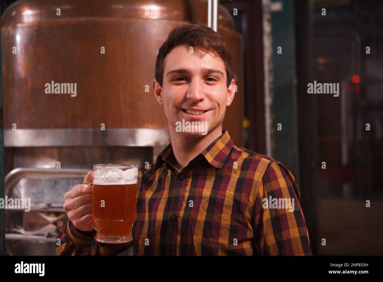 Happy young professional brewer smiling, holding beer mug Stock Photo ...
