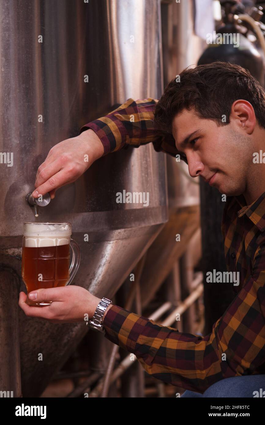 Vertical cropped shot of a professional brewer pouring freshly brewed ...