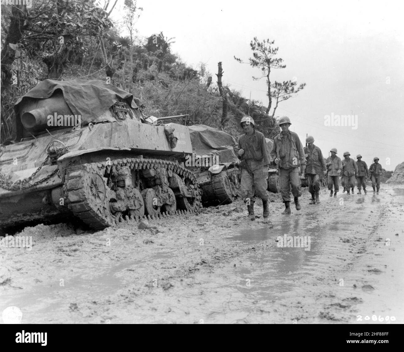 SC 208600 - Soldiers of the 77th Inf. Div. walk past mud-clogged tanks ...