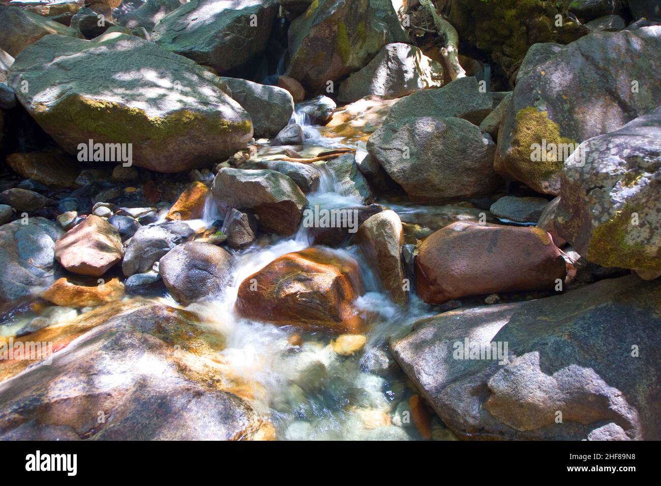 colorful stones in the clear cold water of a creek with water from ...