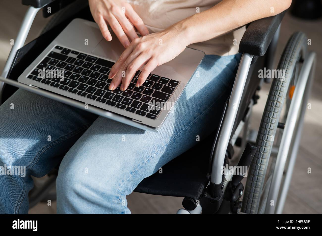 Caucasian woman in a wheelchair typing with a laptop from home. Remote ...
