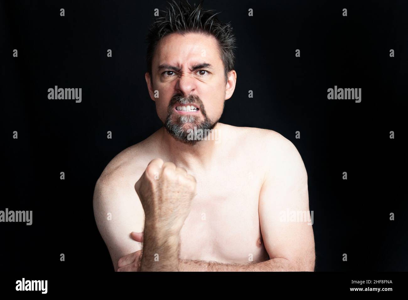 Young adult male with beard and bare torso, looking directly into the ...