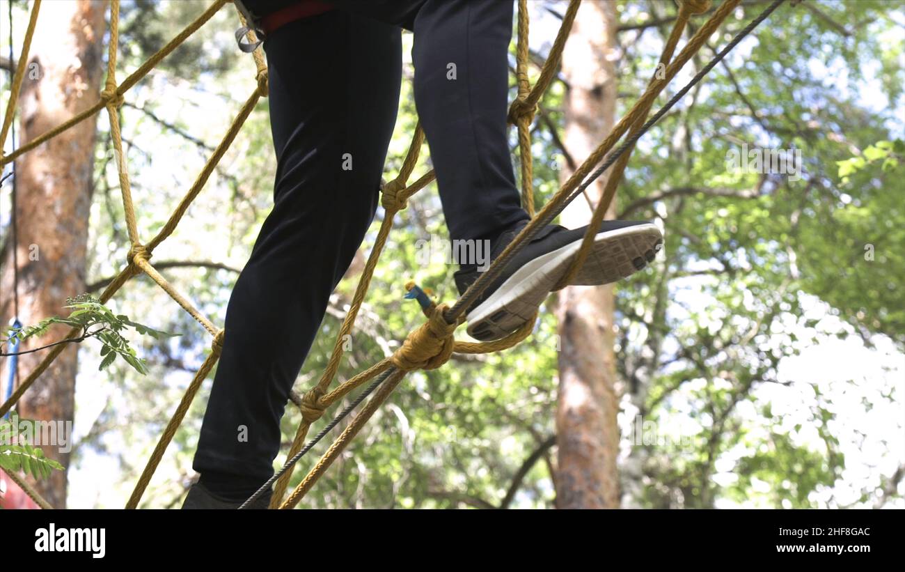 Close up for man on high rope trail in forest adventure park, extreme ...